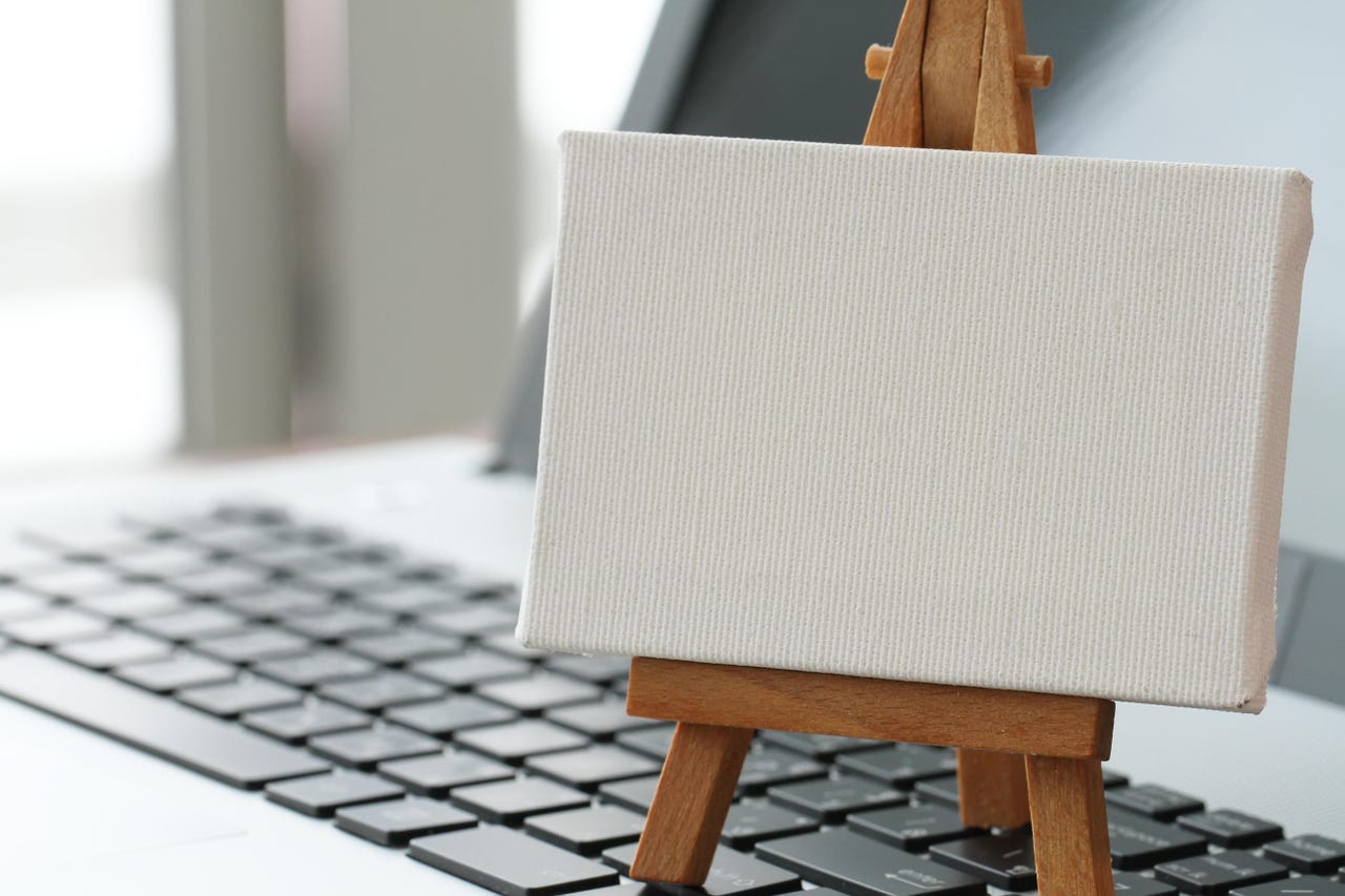 blank canvas and wooden easel on laptop computer blank canvas and wooden easel on laptop computer