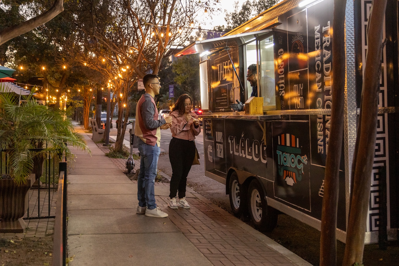 A couple stands beside the Tlaloc taco van food truck in Southtown San ...