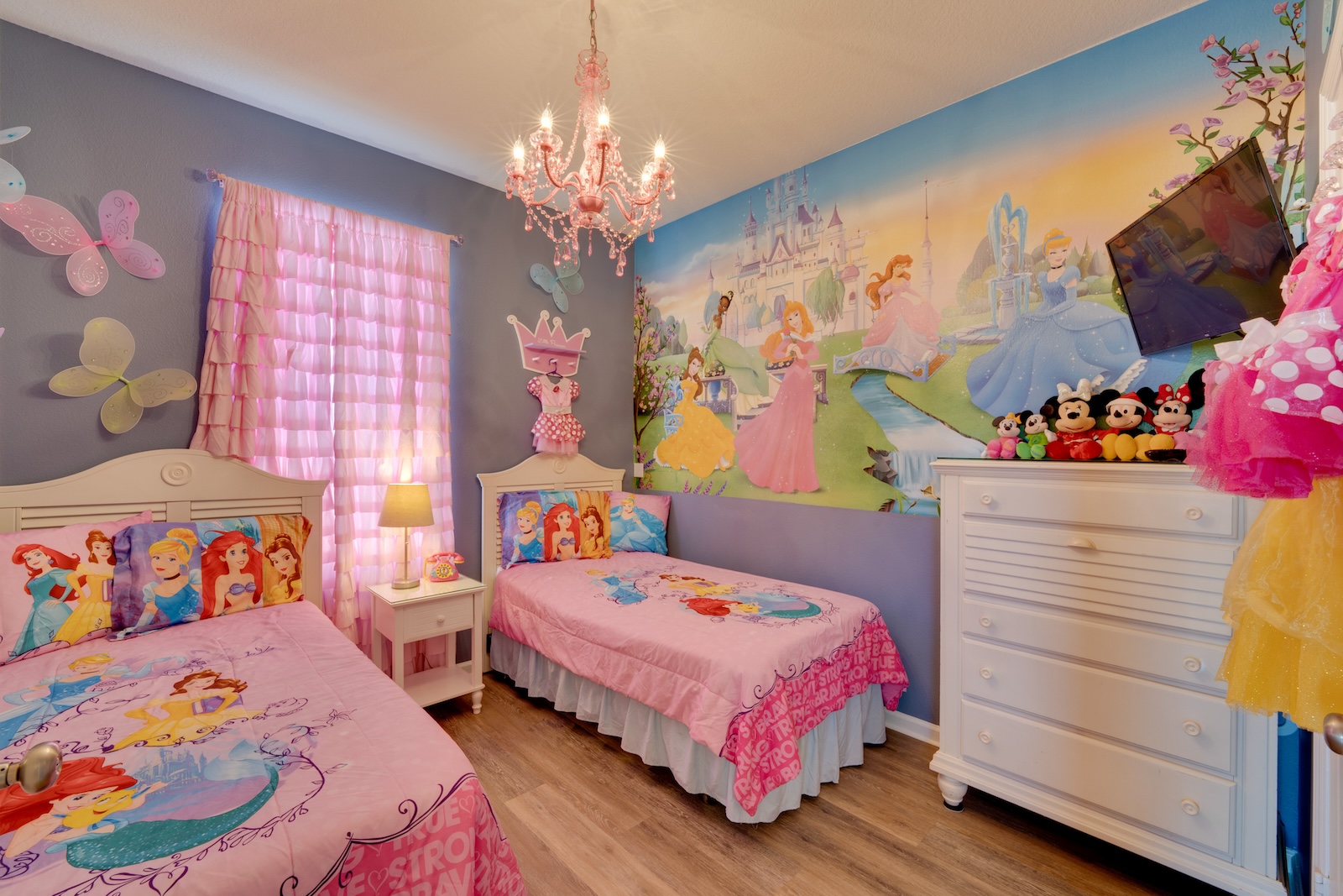 A Disney princess-themed bedroom featuring two twin beds, designed for ...