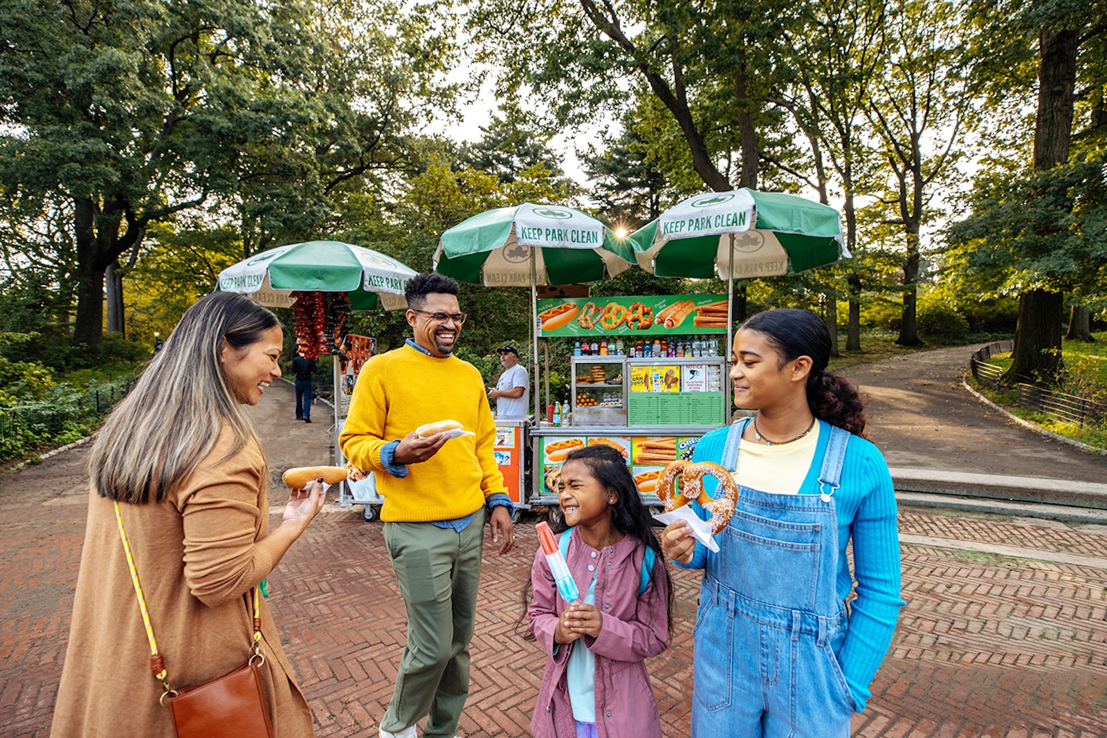 A family stands together in front of a hot dog stand, enjoying a ...