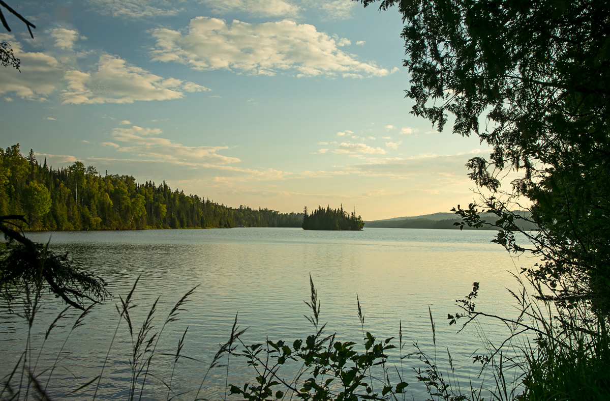 A tranquil scene of Lake Superior, framed by dense forest, showcasing ...