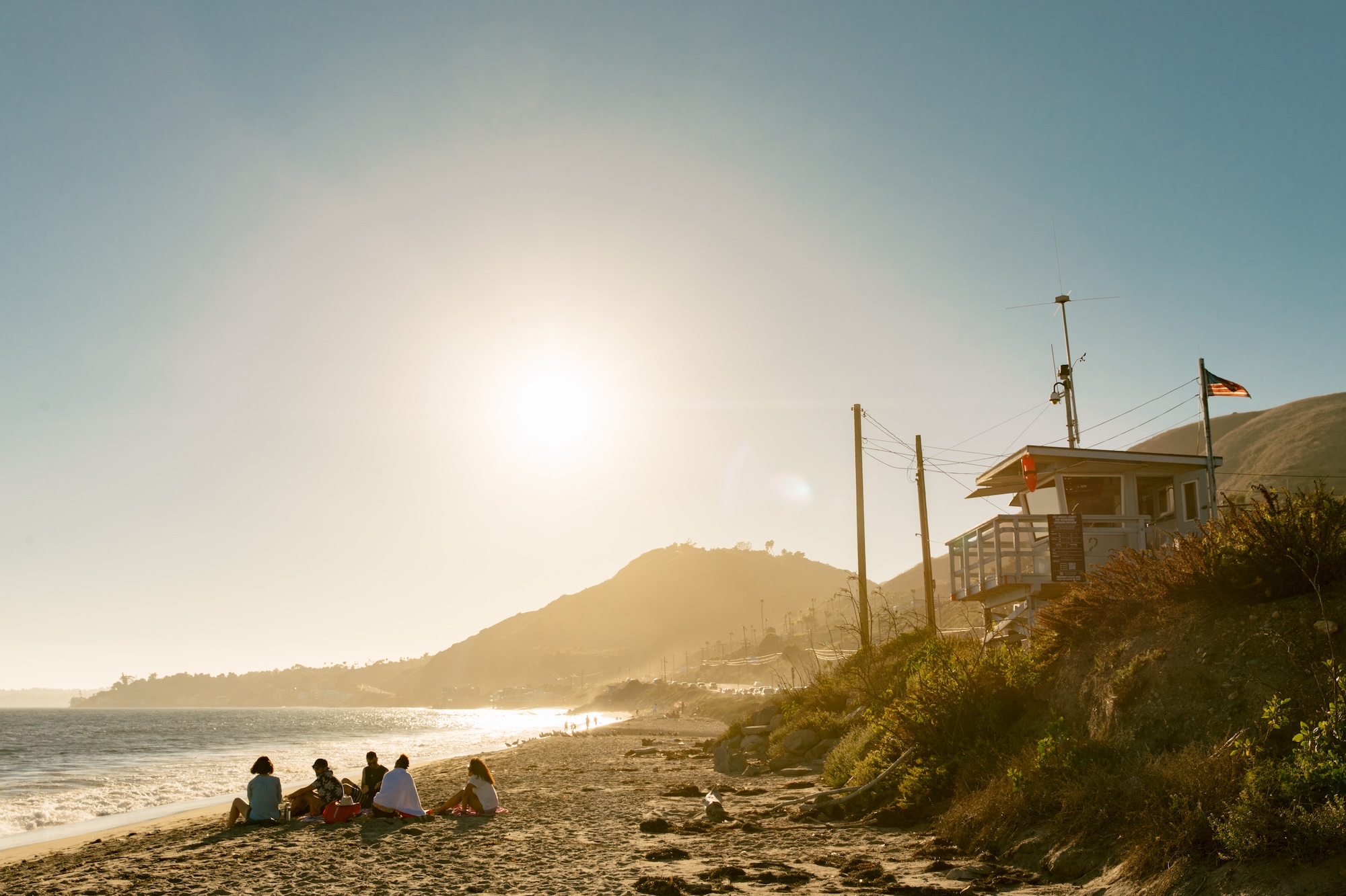 People relaxing on the sandy beach in Malibu, California, soaking up the sun and enjoying the ...
