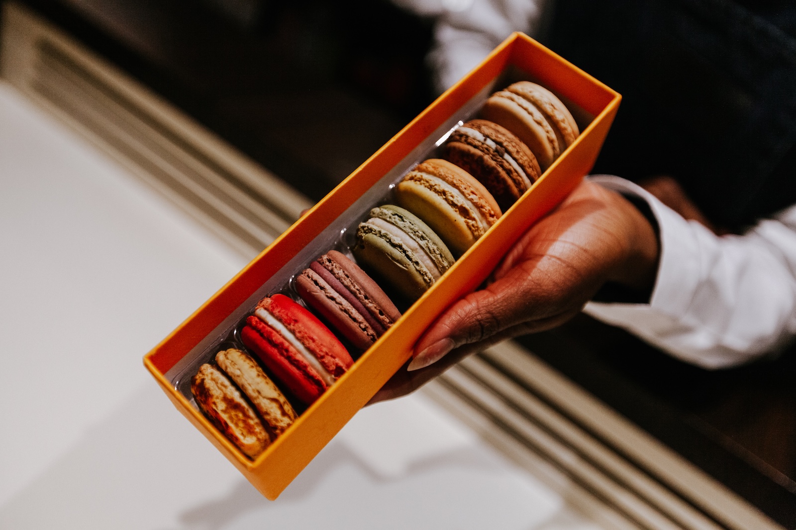 A person in Paris holds an orange box filled with an assortment of ...