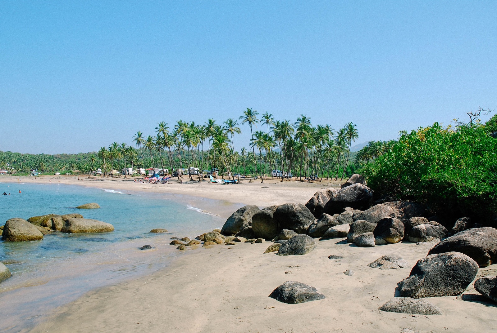 A beach in Agonda featuring rocks and palm trees lining the tranquil ...