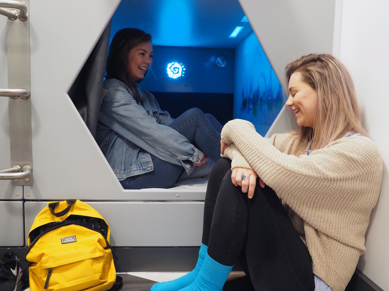 Two women are sat in and around a capsule hotel room in St Christopher ...