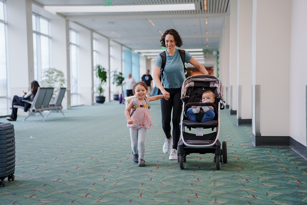 A woman pushes a stroller with a child inside and holds hands with ...