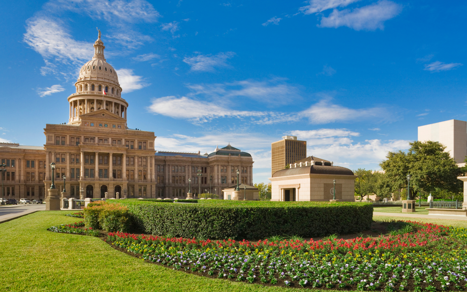 En primer plano aparece vegetación y, de fondo, el Capitolio de Texas ...